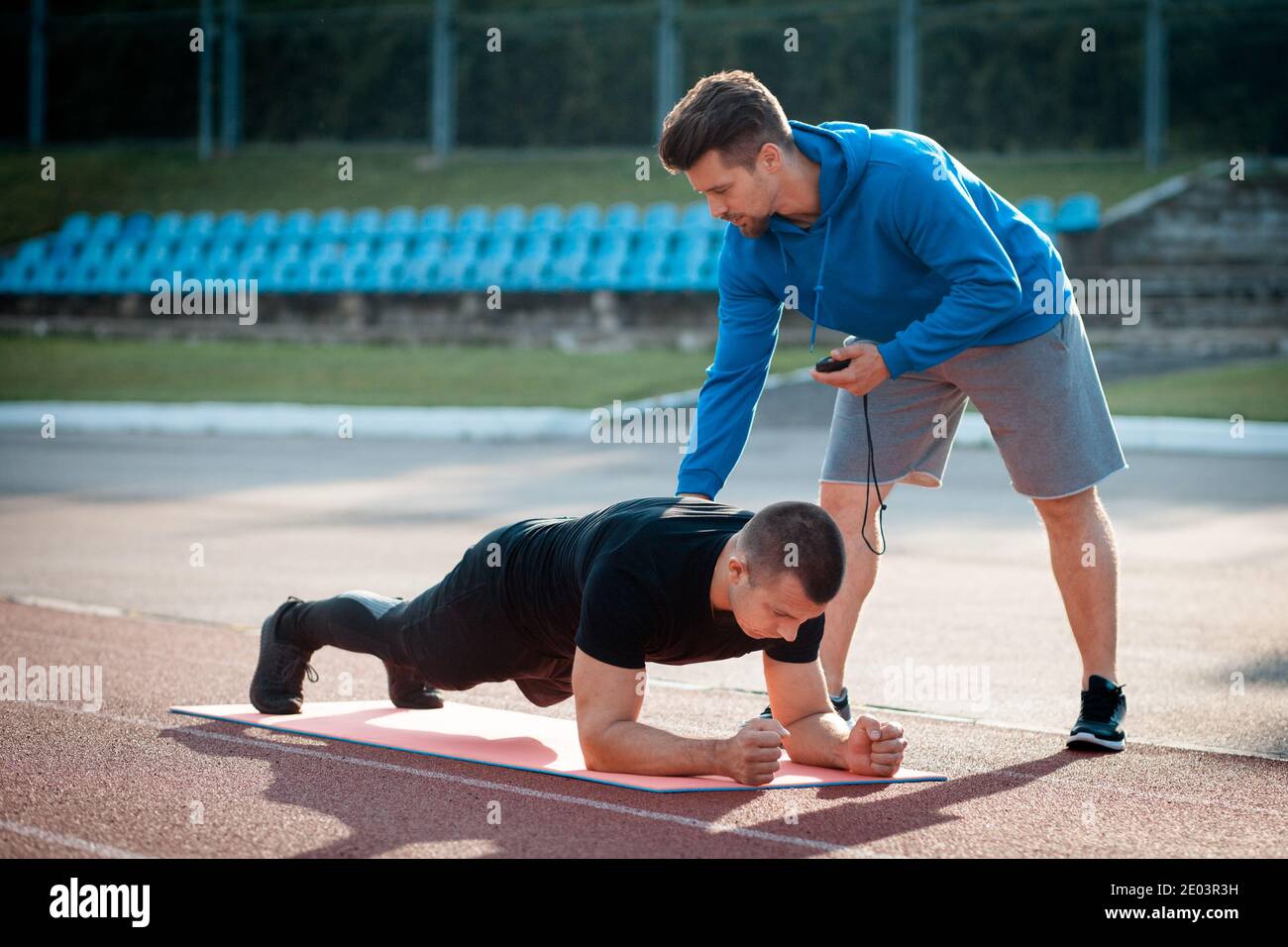 man doing plank exercise and workout with personal fitness trainer ...