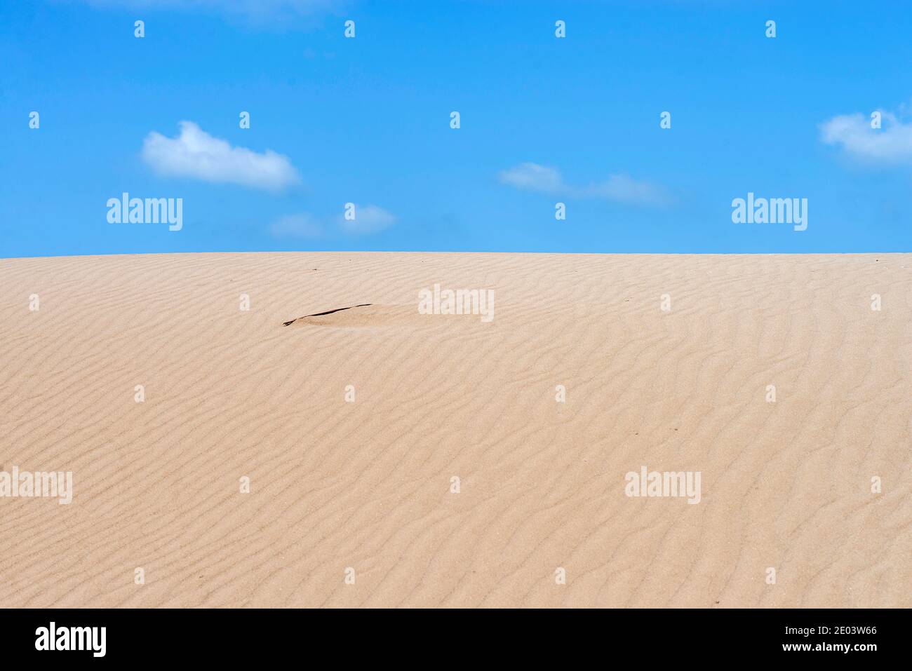 Sand dune under a blue and cloudy sky Stock Photo - Alamy