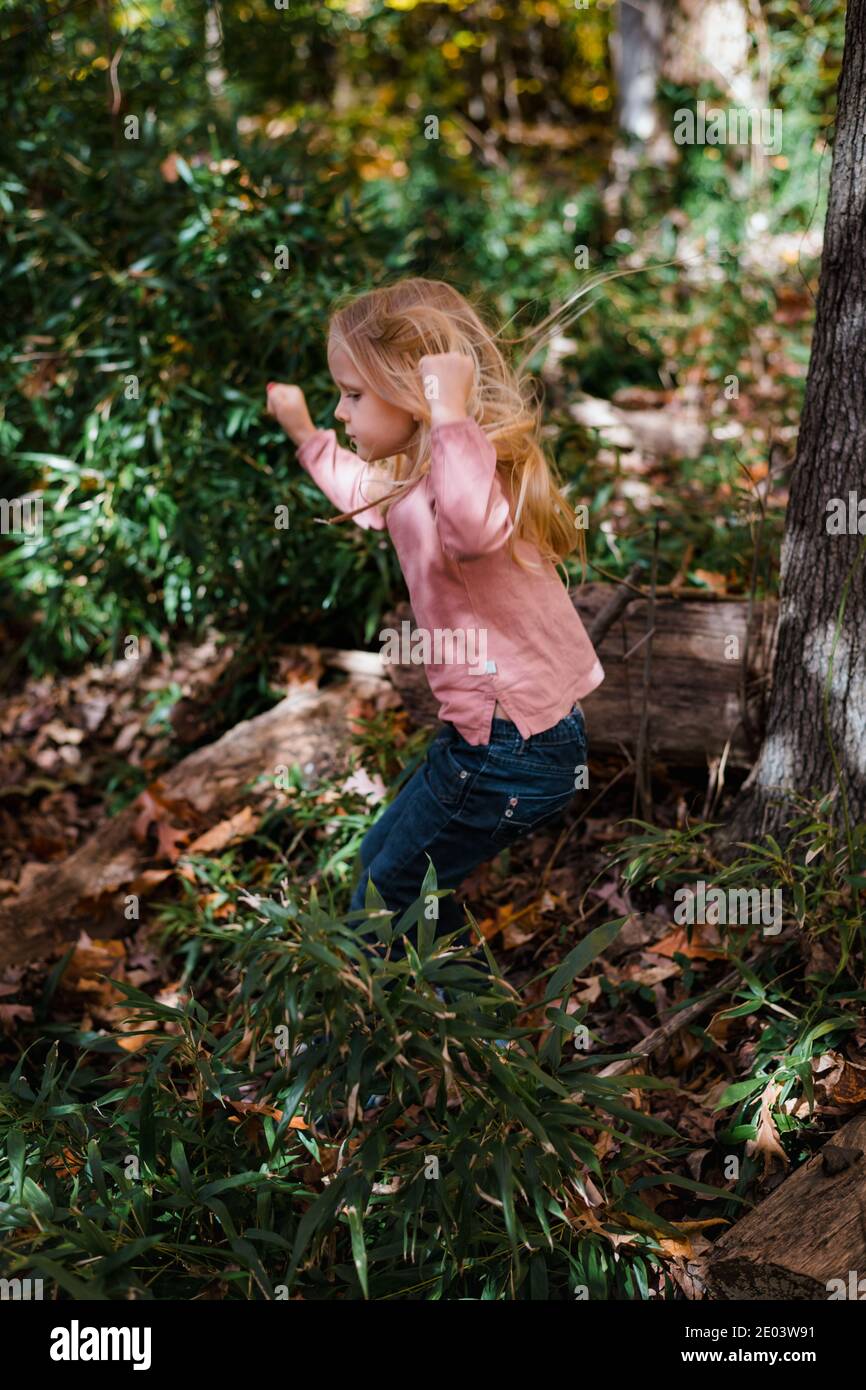 Brave little girl jumping from tree while playing in forest Stock Photo ...