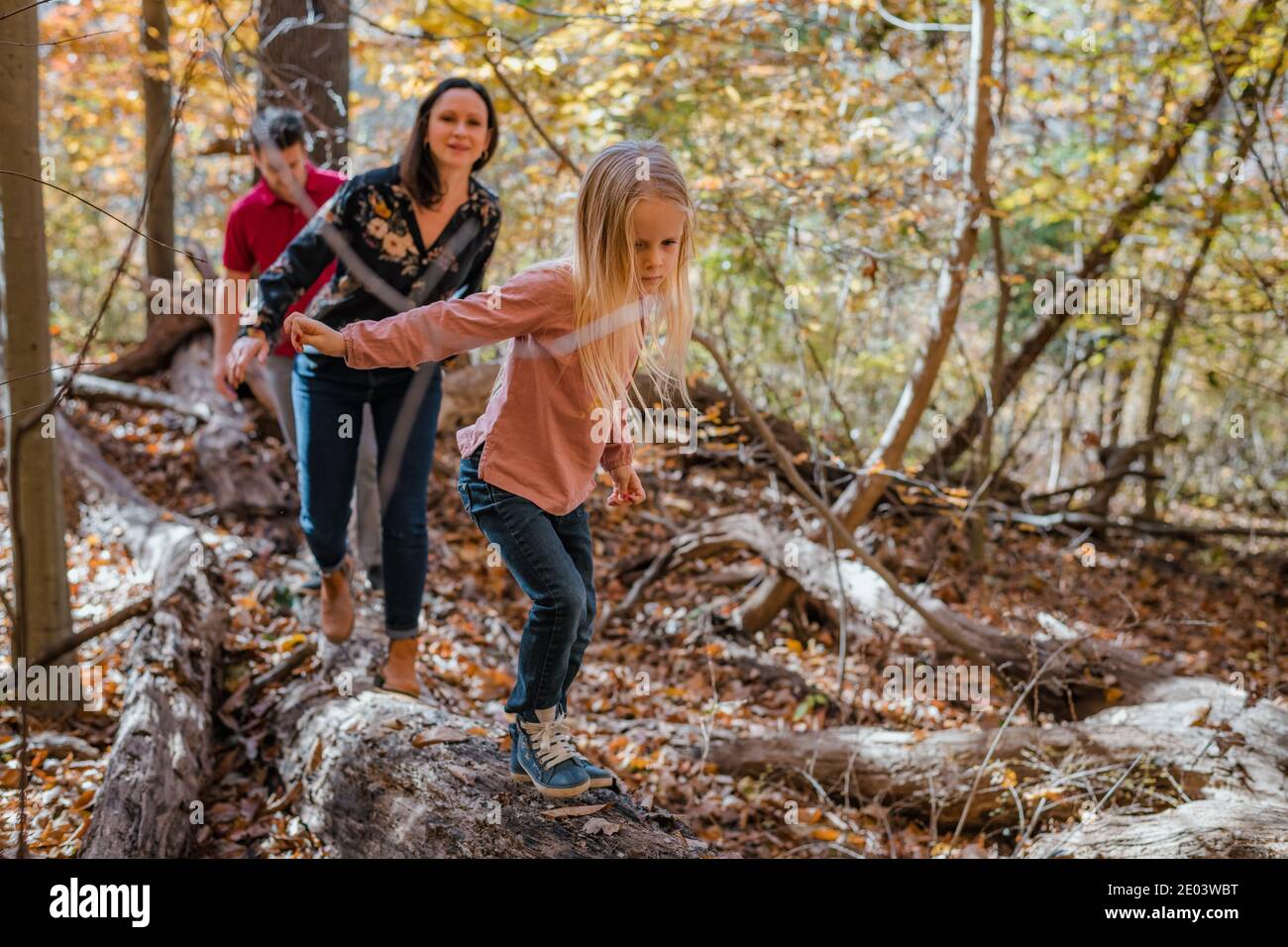 Parents and little girl balancing on forest log Stock Photo - Alamy