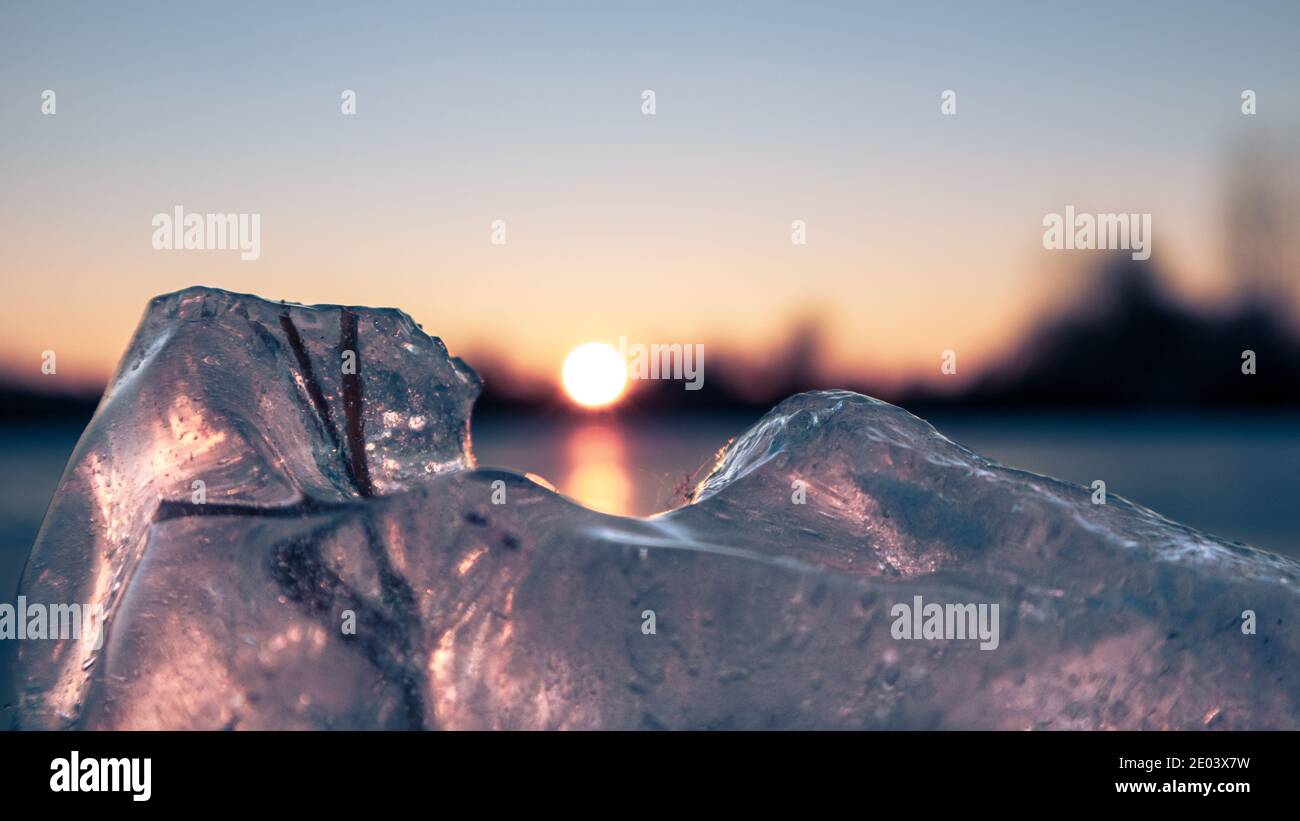 View on sunset sun through transparent clear ice close-up sparkling on ...