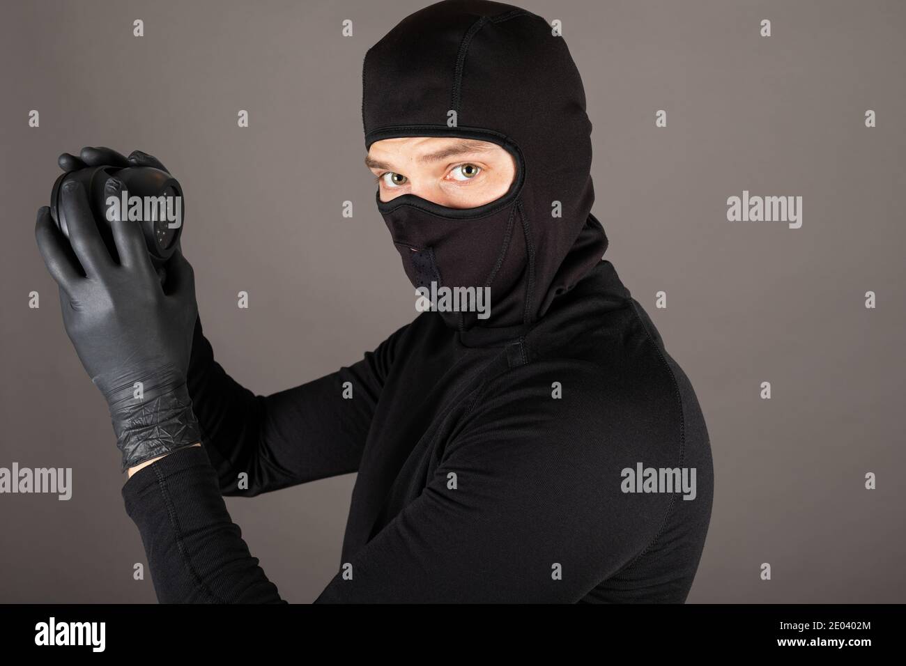Picture of a thief dressed in black costume and wearing mask trying to ...