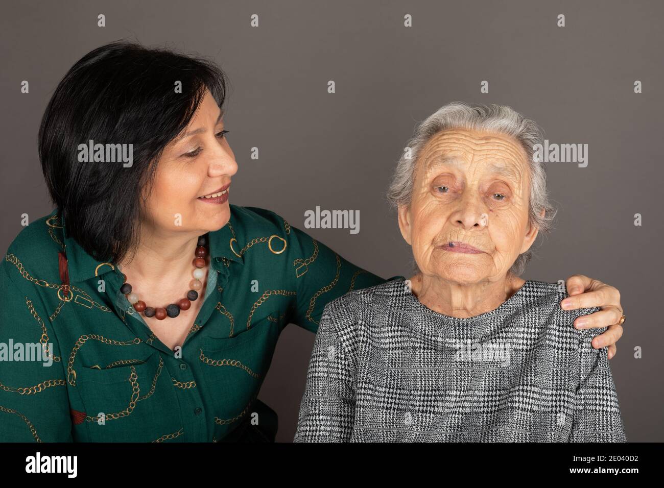 Studio portrait of middle aged woman with her retired mother cuddling ...