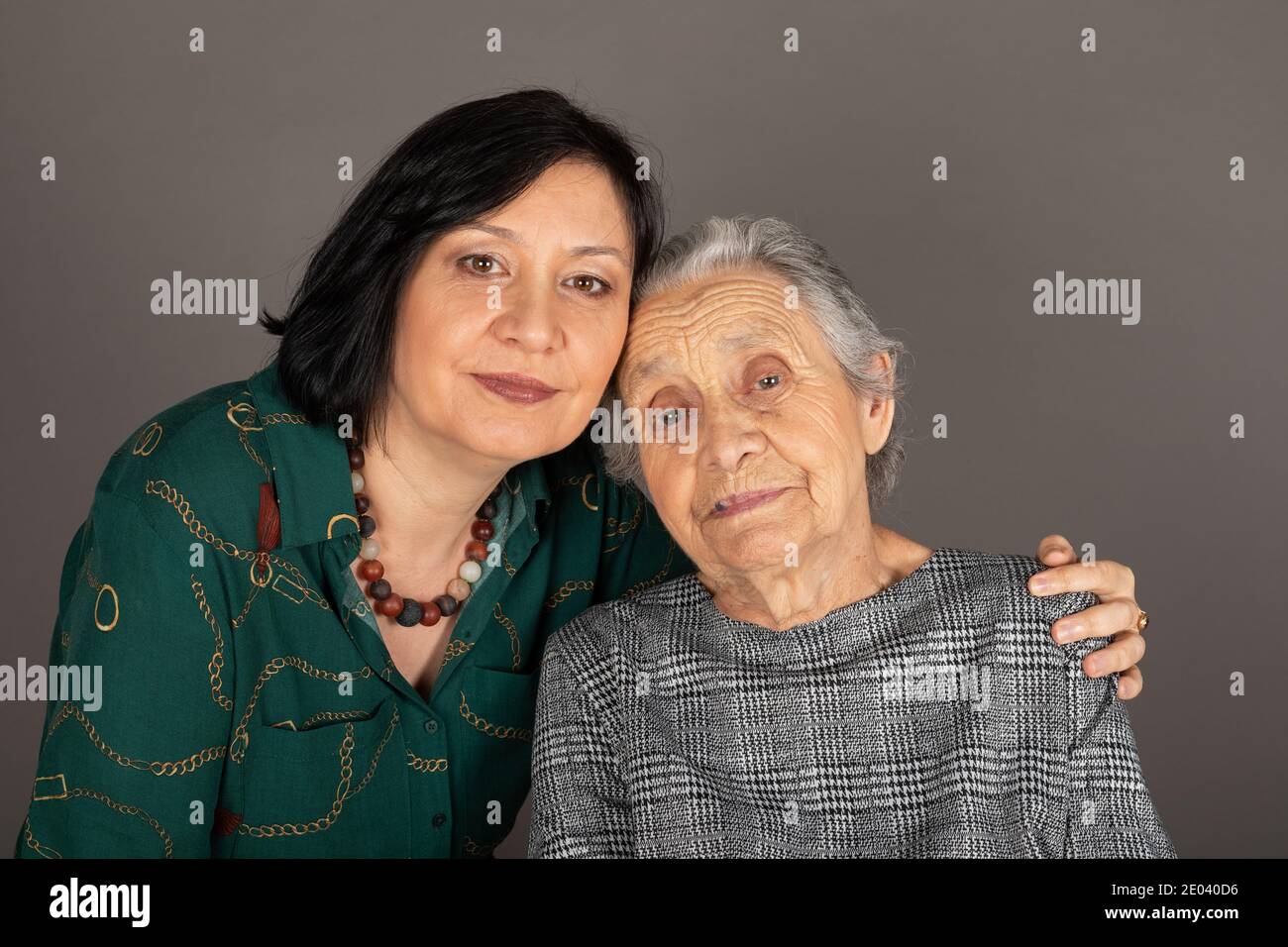 Studio portrait of middle aged woman with her retired mother cuddling ...