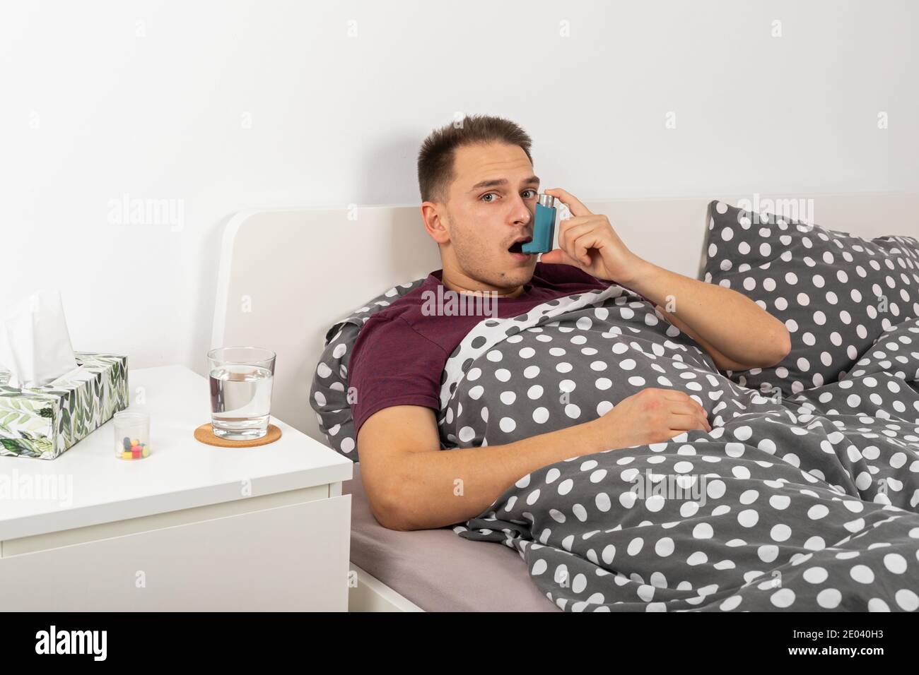 Young male patient with seasonal influenza is using an inhaler with ...