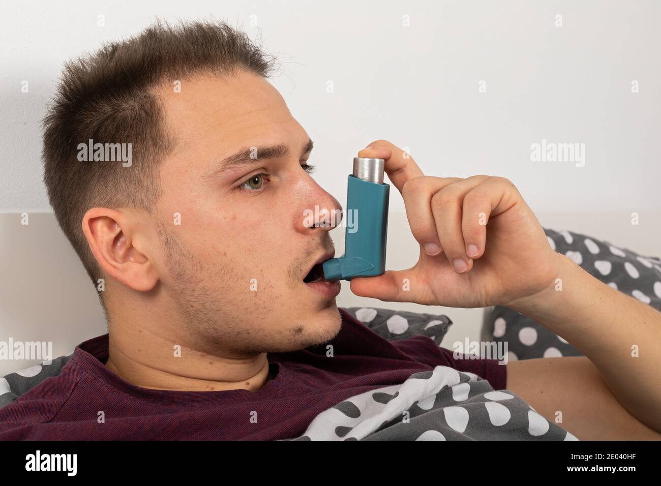 Young male patient with seasonal influenza is using an inhaler with ...