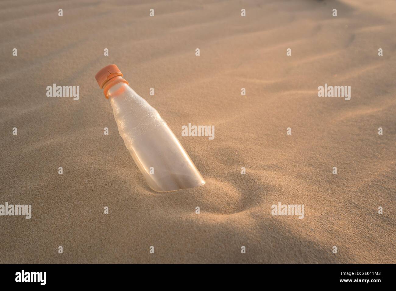A bottle half buried in the sand Stock Photo - Alamy