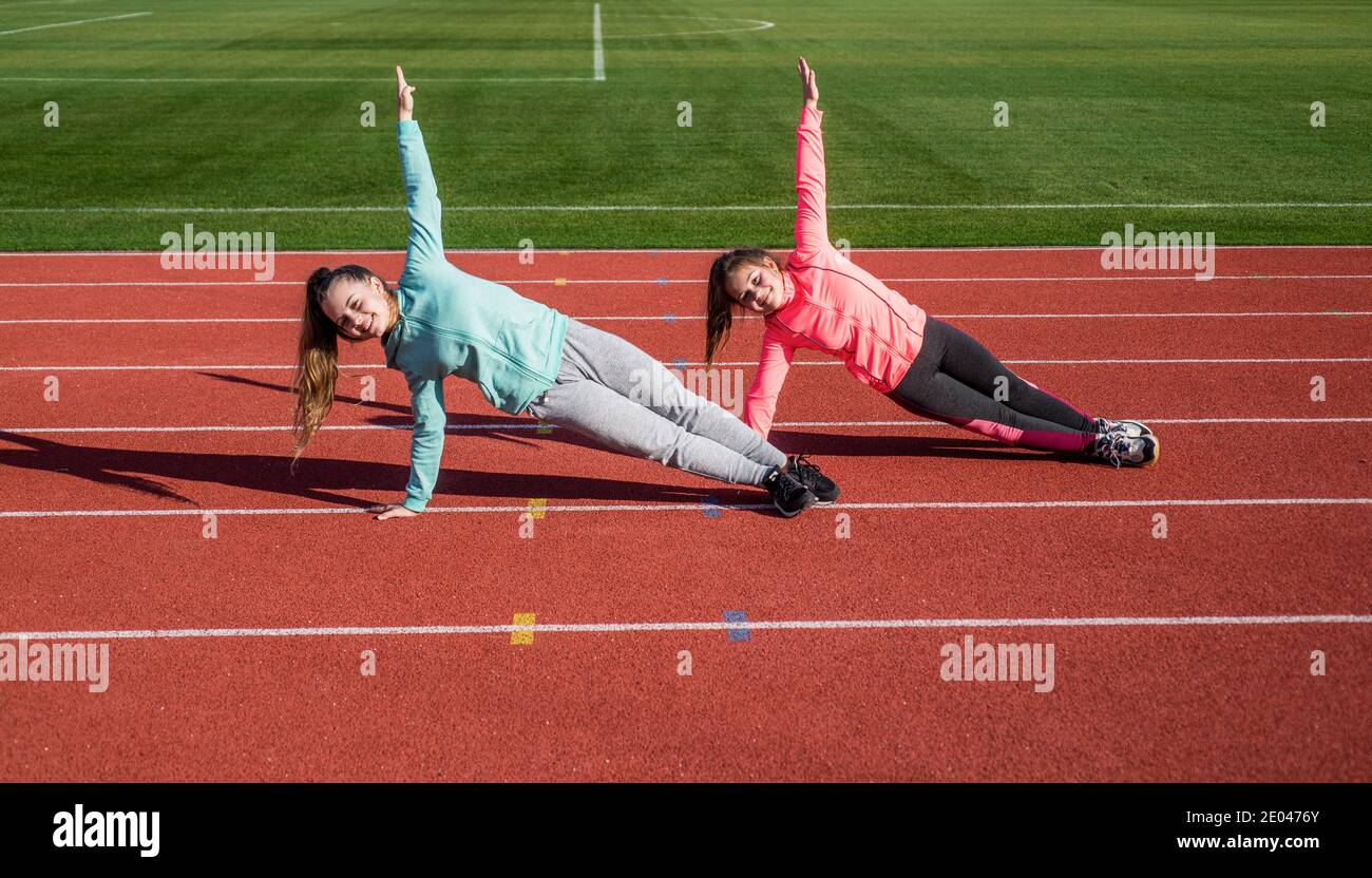 Towards the healthier lifestyle. teenage girls standing in side plank ...