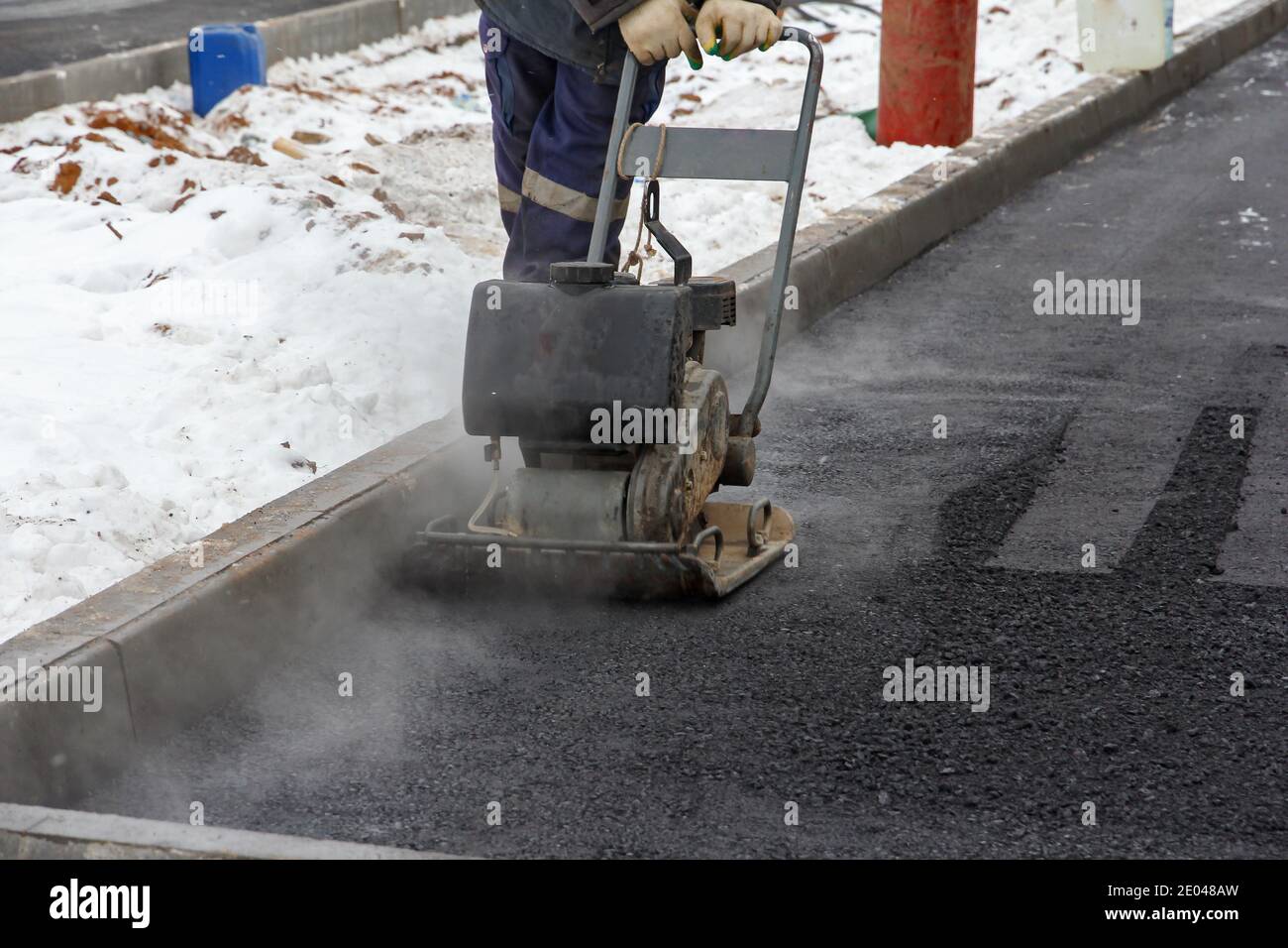 Worker use vibratory plate compactor for ramming asphalt. Men at work ...