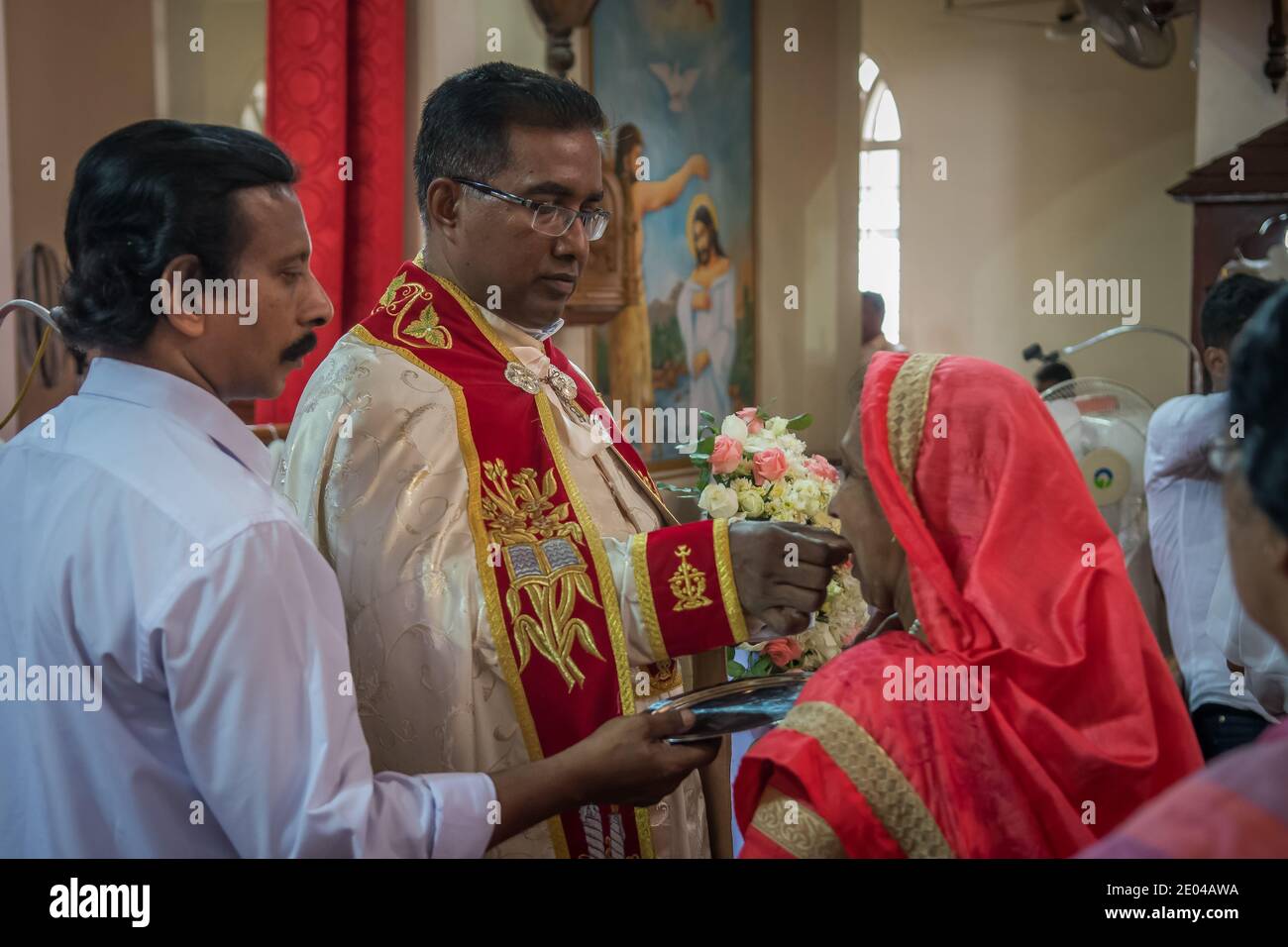 Kerala, India, 08-12-2017. Priest giving body of christ to family ...
