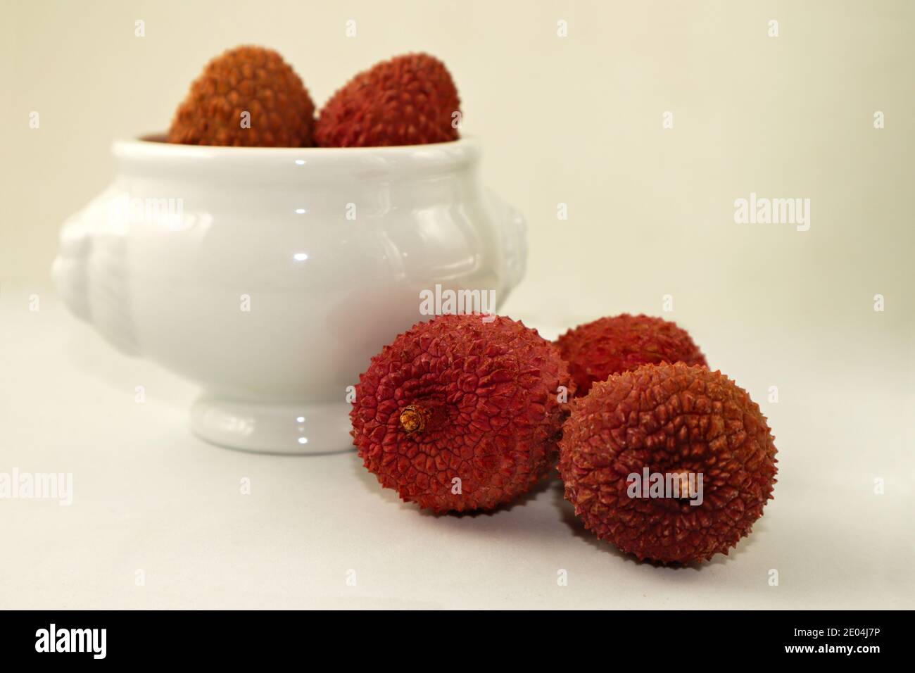 Image of some lychees in a bowl and on a white table and background ...