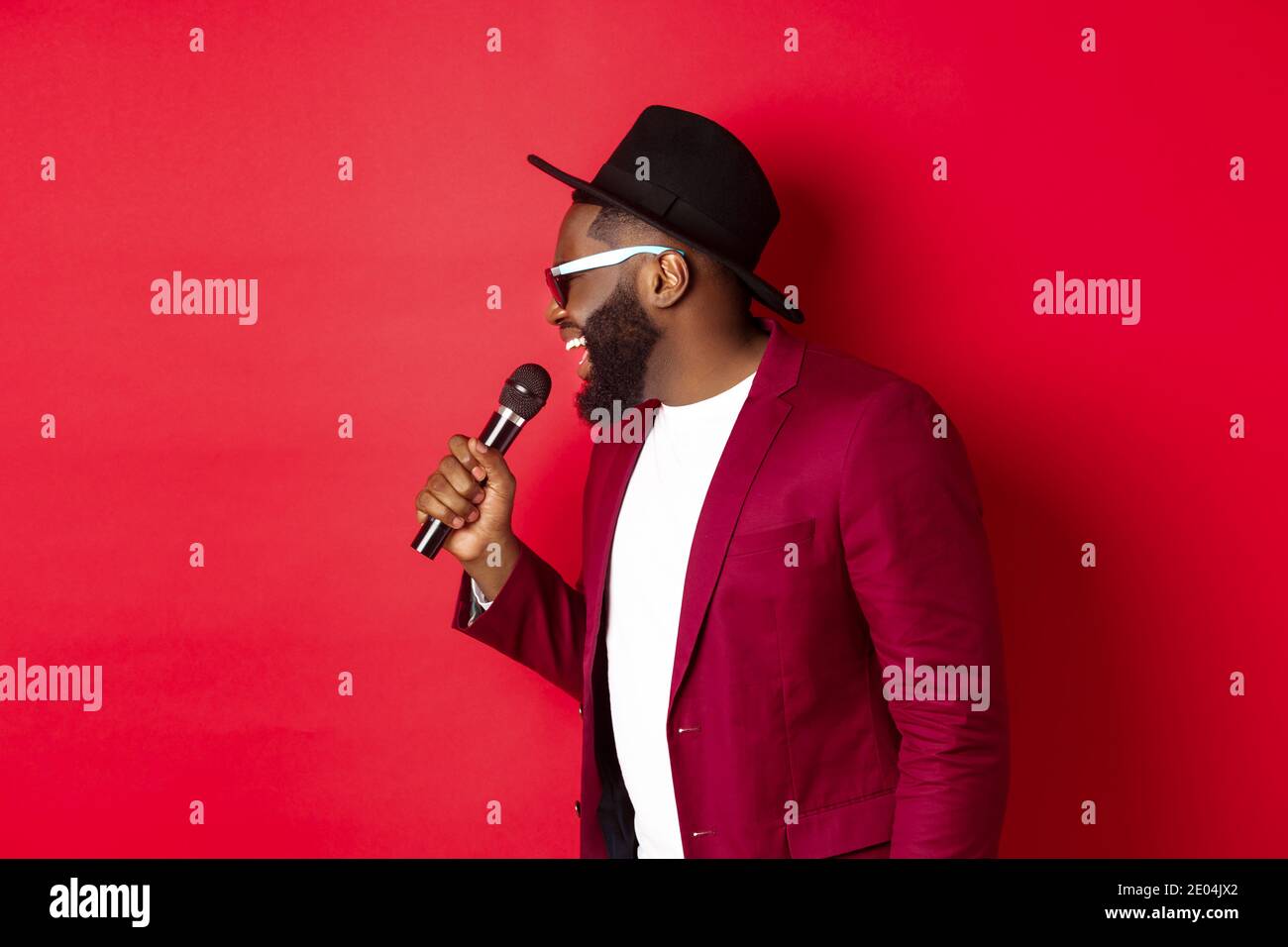 Passionate black male singer performing against red background, singing ...