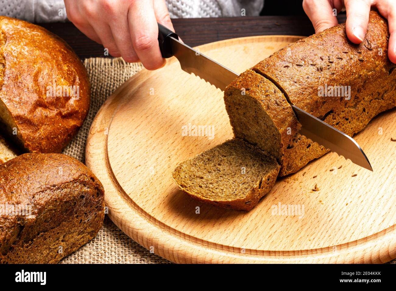 Women's hands cut a loaf of bread. Rye bread on a cutting board Stock ...