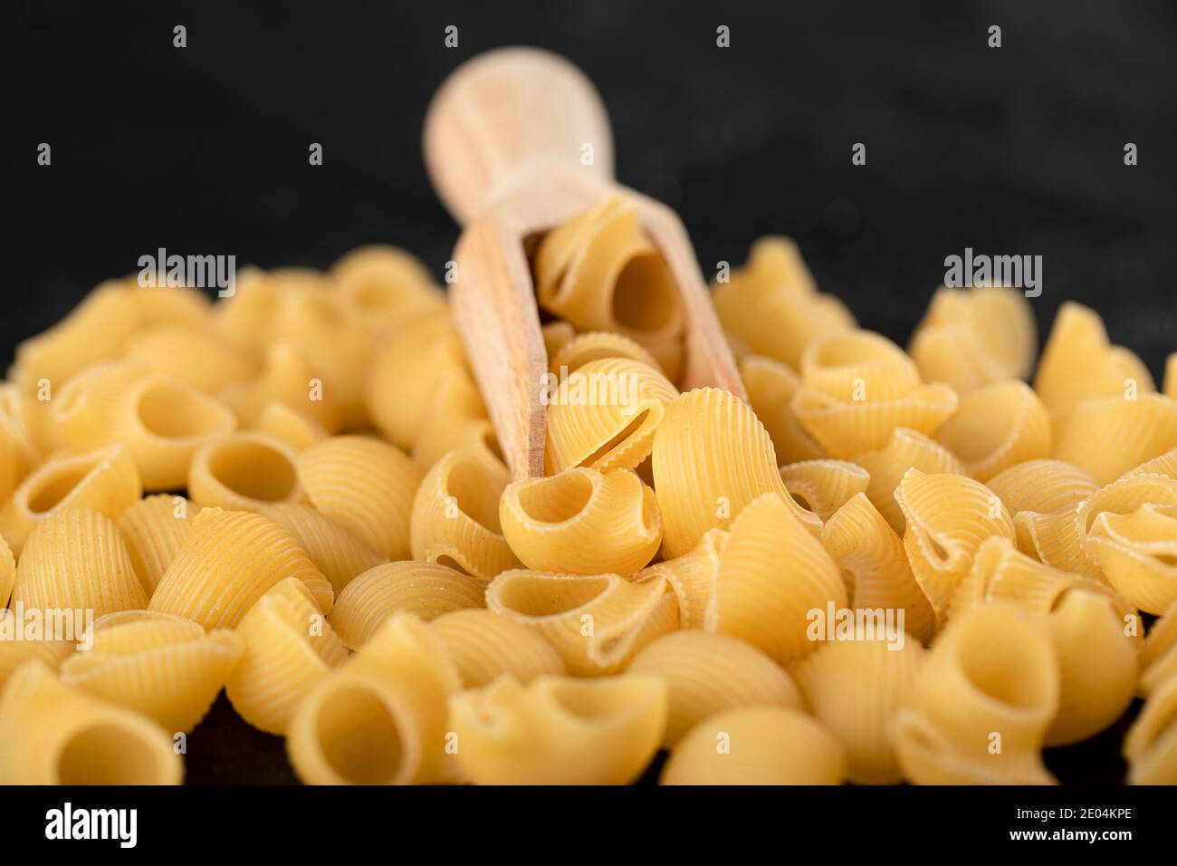 Raw seashell shaped pasta on black background Stock Photo - Alamy