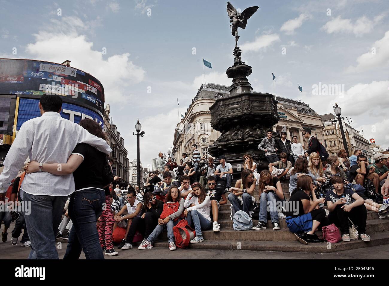 People crossing street and sit on steps of monument at Piccadilly ...