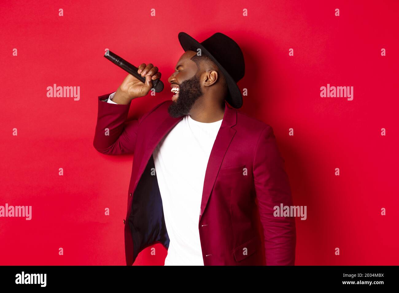 Passionate black male singer performing against red background, singing ...