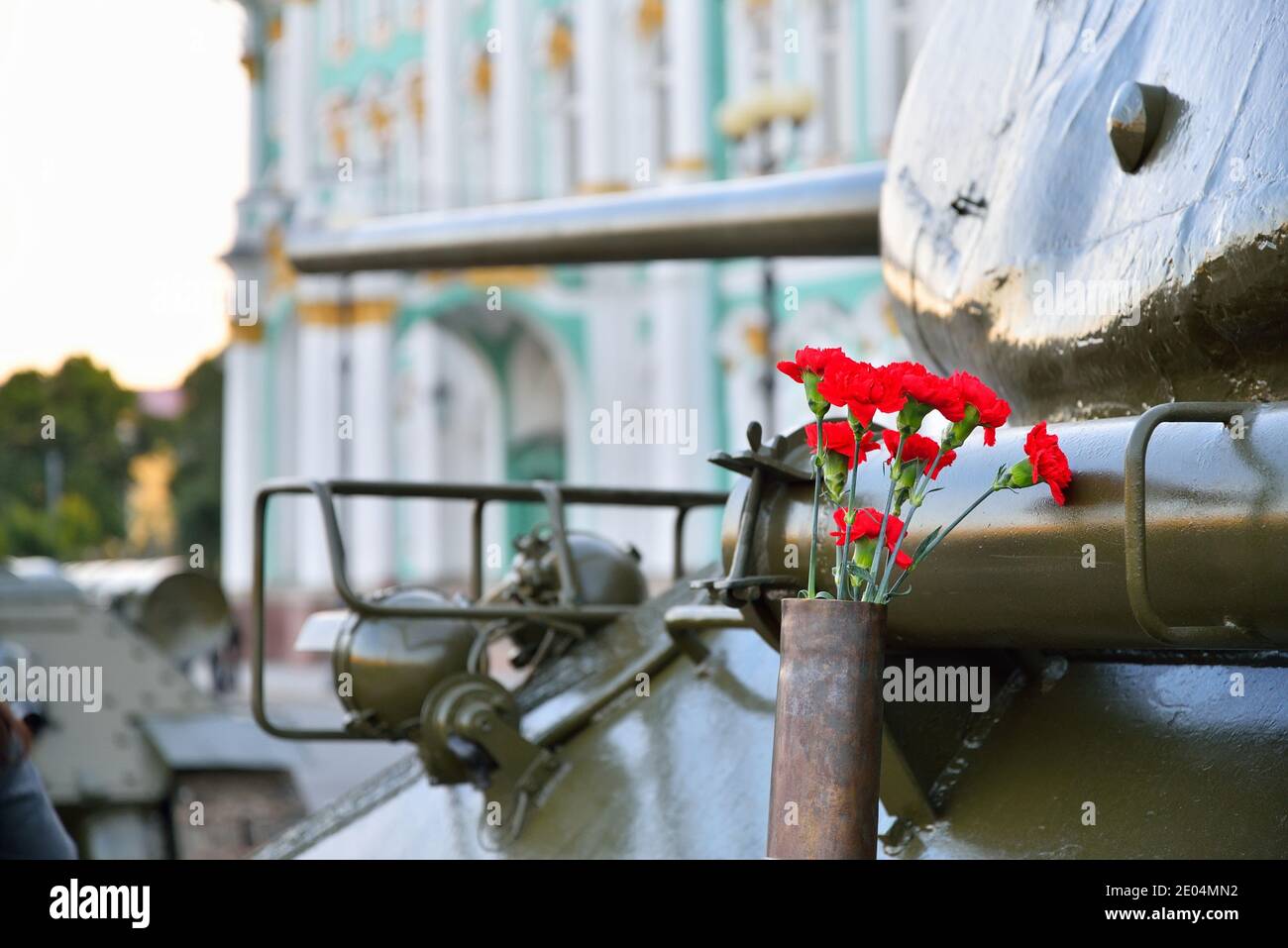 Red carnations in a gun shell closeup on the middle of the Soviet tank ...