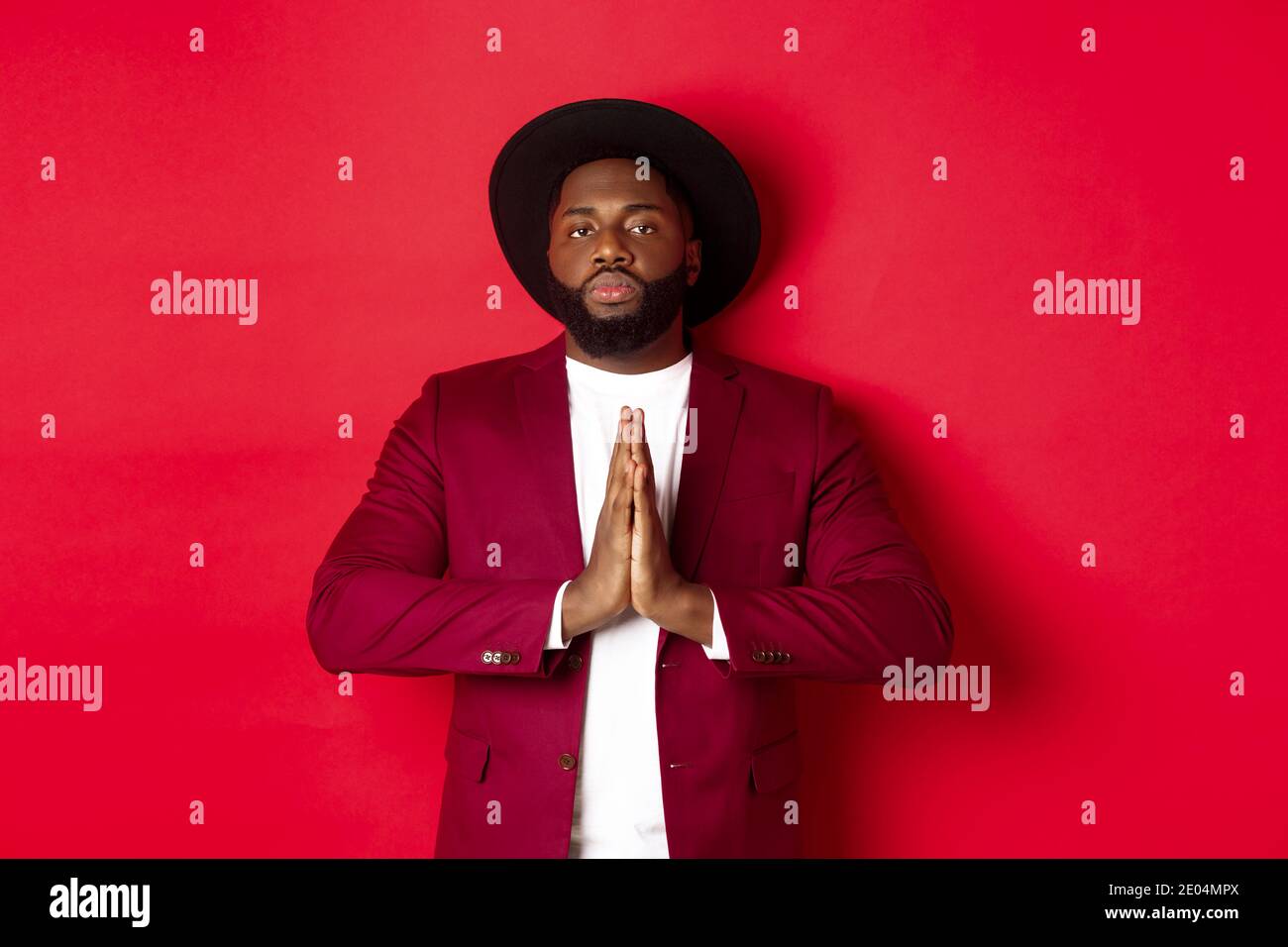 Serious african american man showing respect, holding hands together in ...
