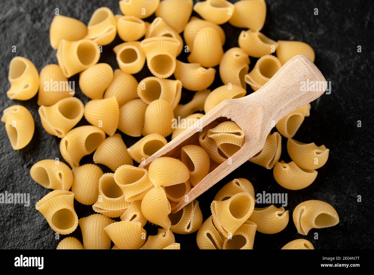 Raw seashell shaped pasta on black background Stock Photo - Alamy