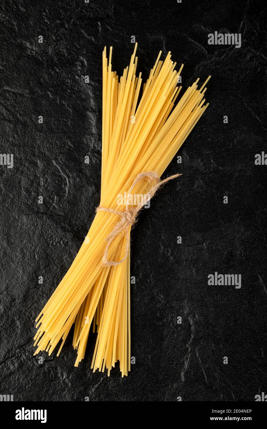 Raw spaghetti tied with rope on black background Stock Photo - Alamy