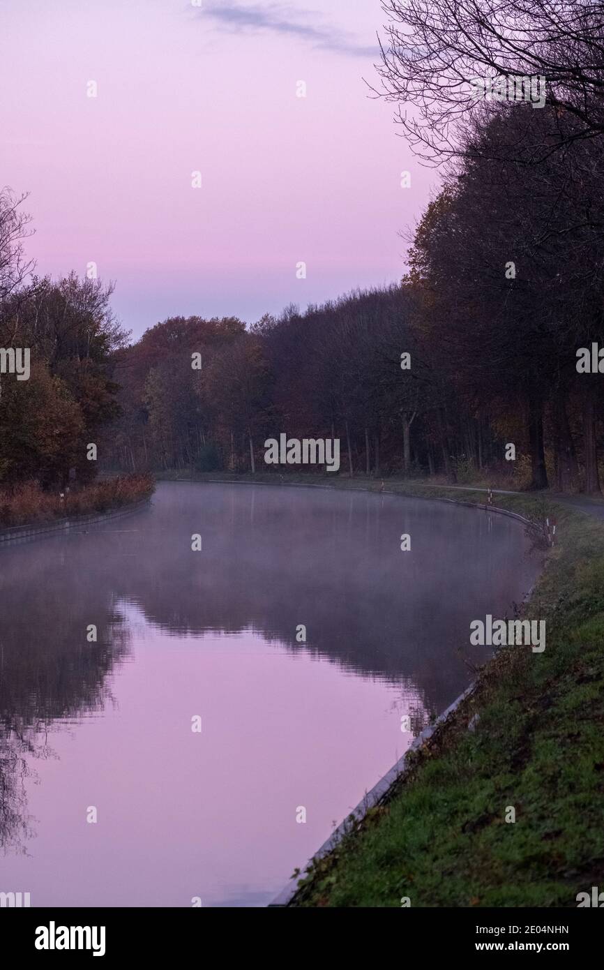 River stream canal bending with grass banks and wild flowers and trees ...