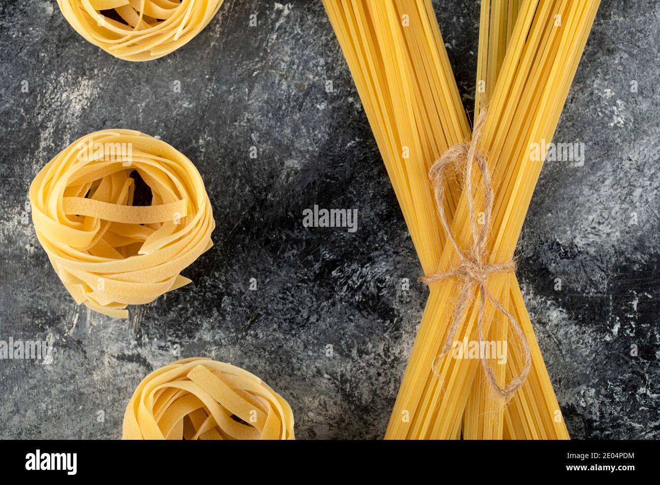 Dry tagliatelle nests and spaghetti on marble background Stock Photo ...