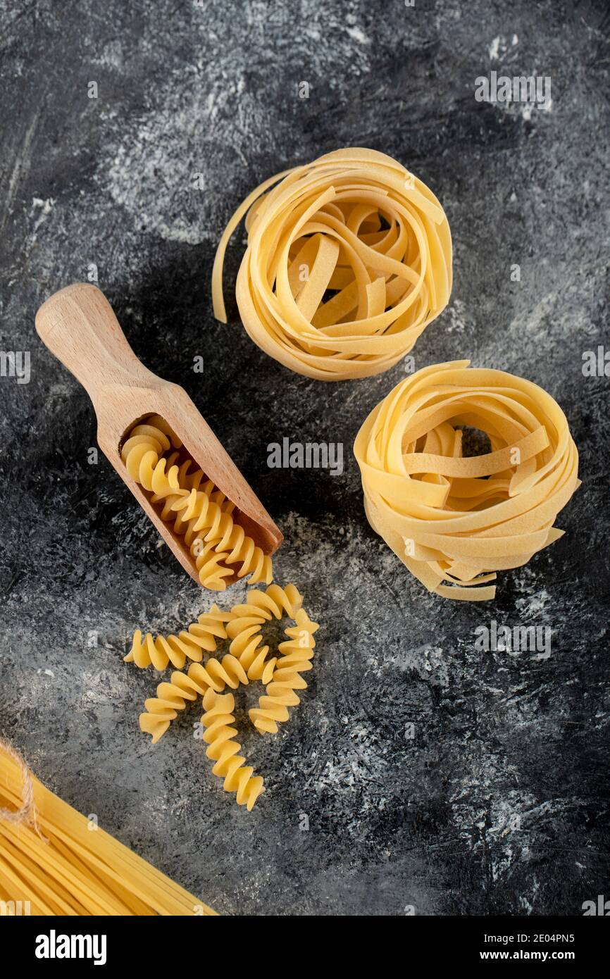 Tagliatelle nests and fusilli on marble background Stock Photo - Alamy
