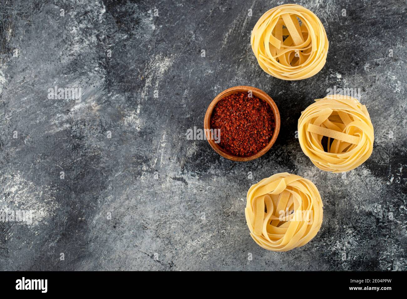 Dry tagliatelle nests and ground red pepper on marble background Stock ...