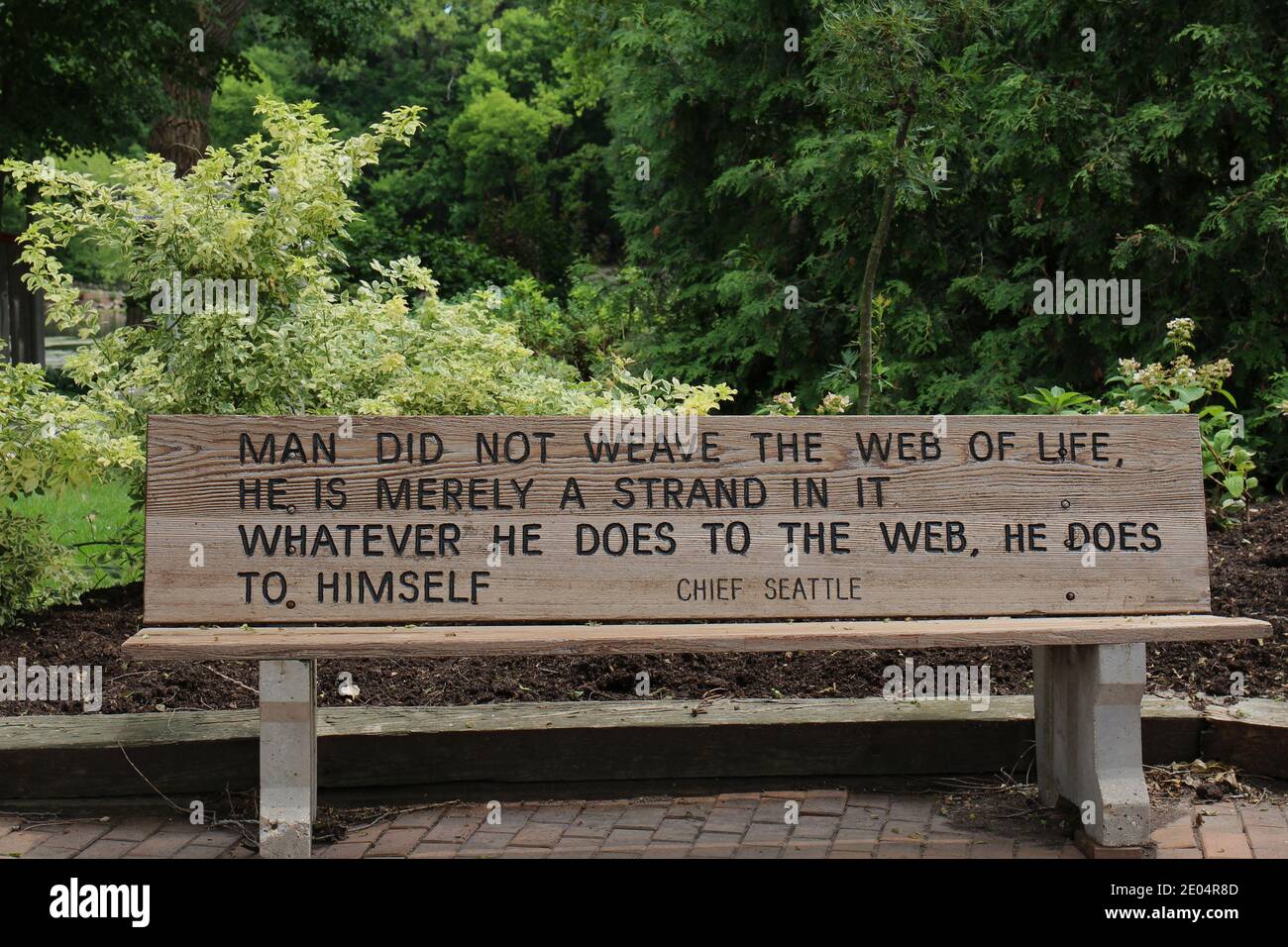 A park bench engraved with a quote from Chief Seattle on a brick path ...