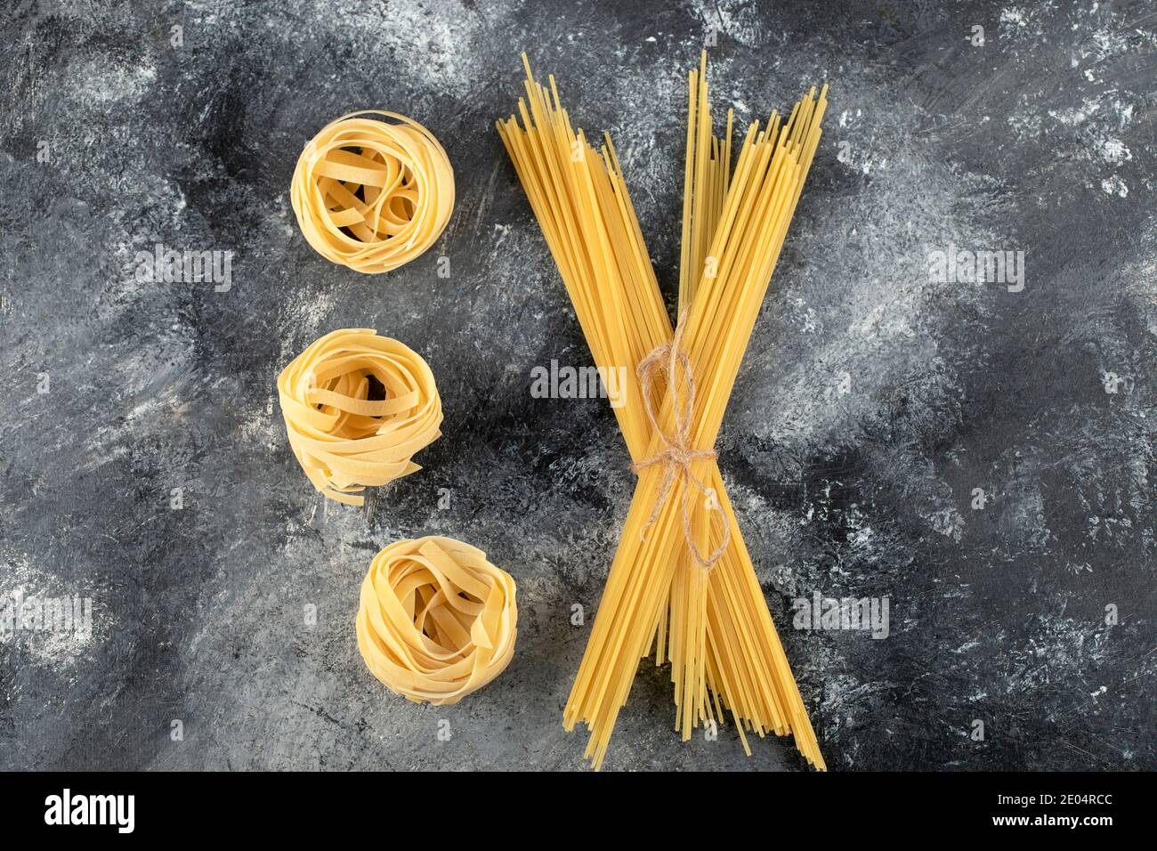 Dry tagliatelle nests and spaghetti on marble background Stock Photo ...