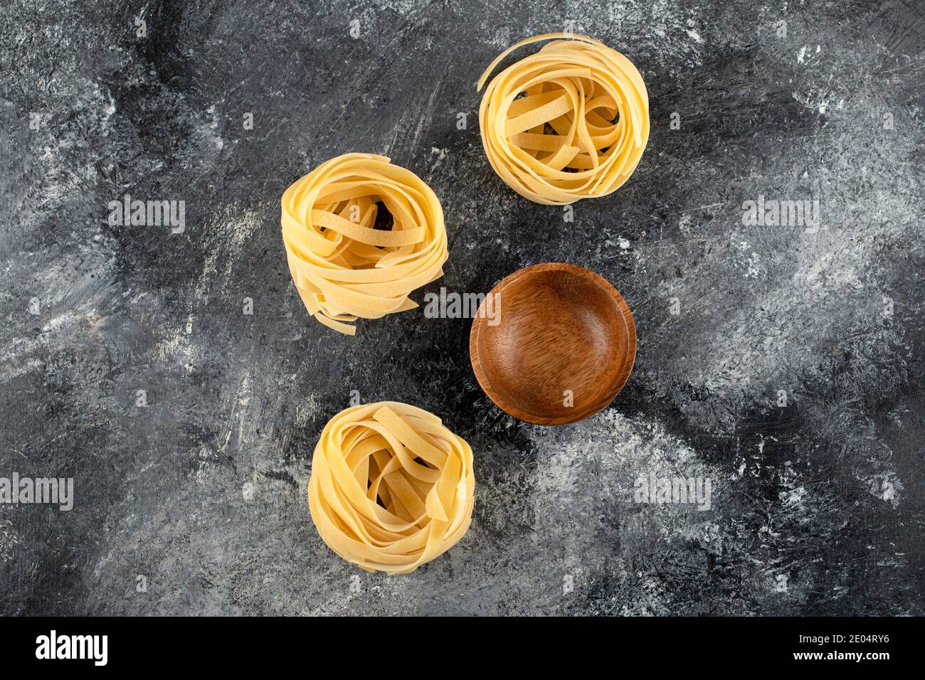 Dry tagliatelle nests and wooden bowl on marble background Stock Photo ...