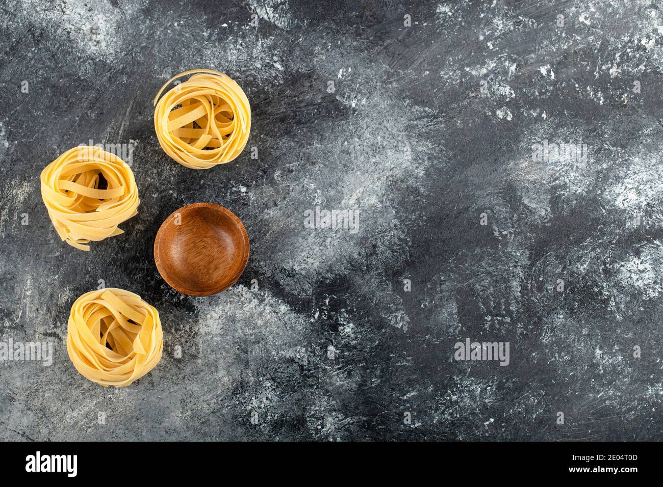 Dry tagliatelle nests and wooden bowl on marble background Stock Photo ...