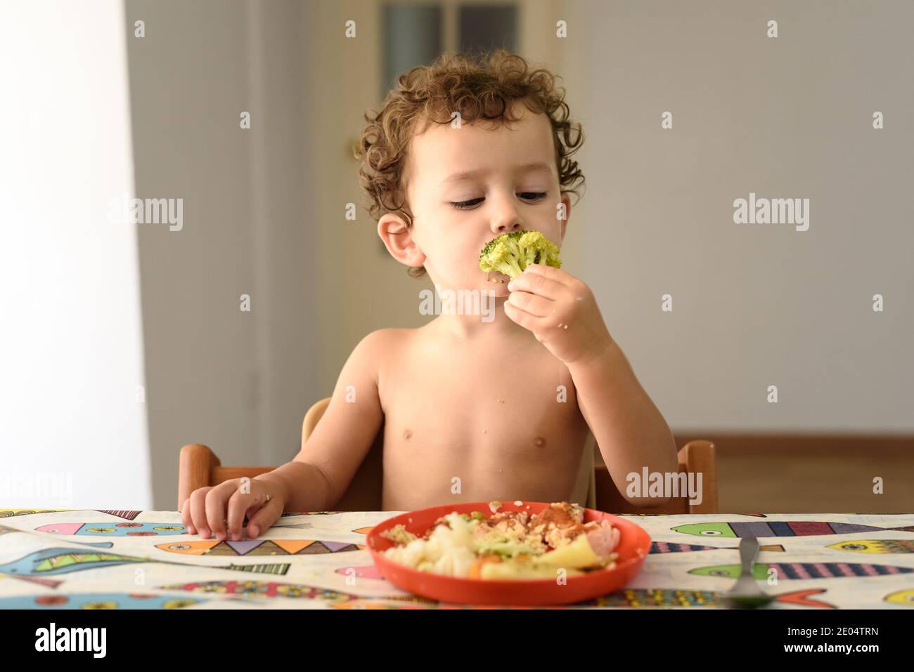 A two-year-old baby feeds herself using her hands in a healthy way ...