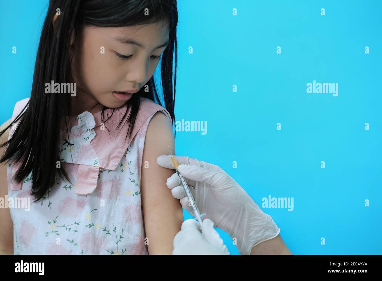 A cute young Asian girl getting a vaccine injection on her arm with ...