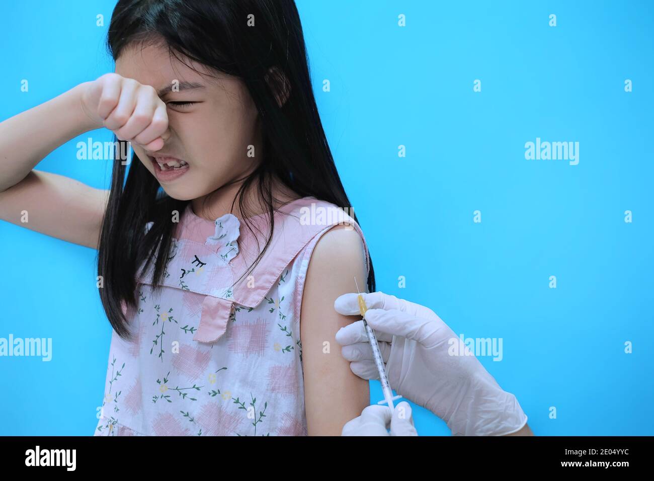 A cute young Asian girl getting a vaccine injection on her arm with ...