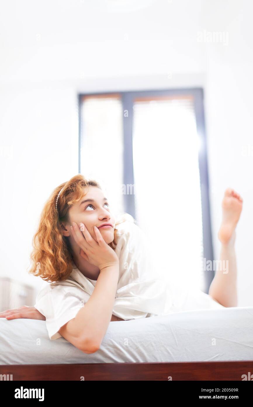 Girl lying on a bed, looking up Stock Photo - Alamy