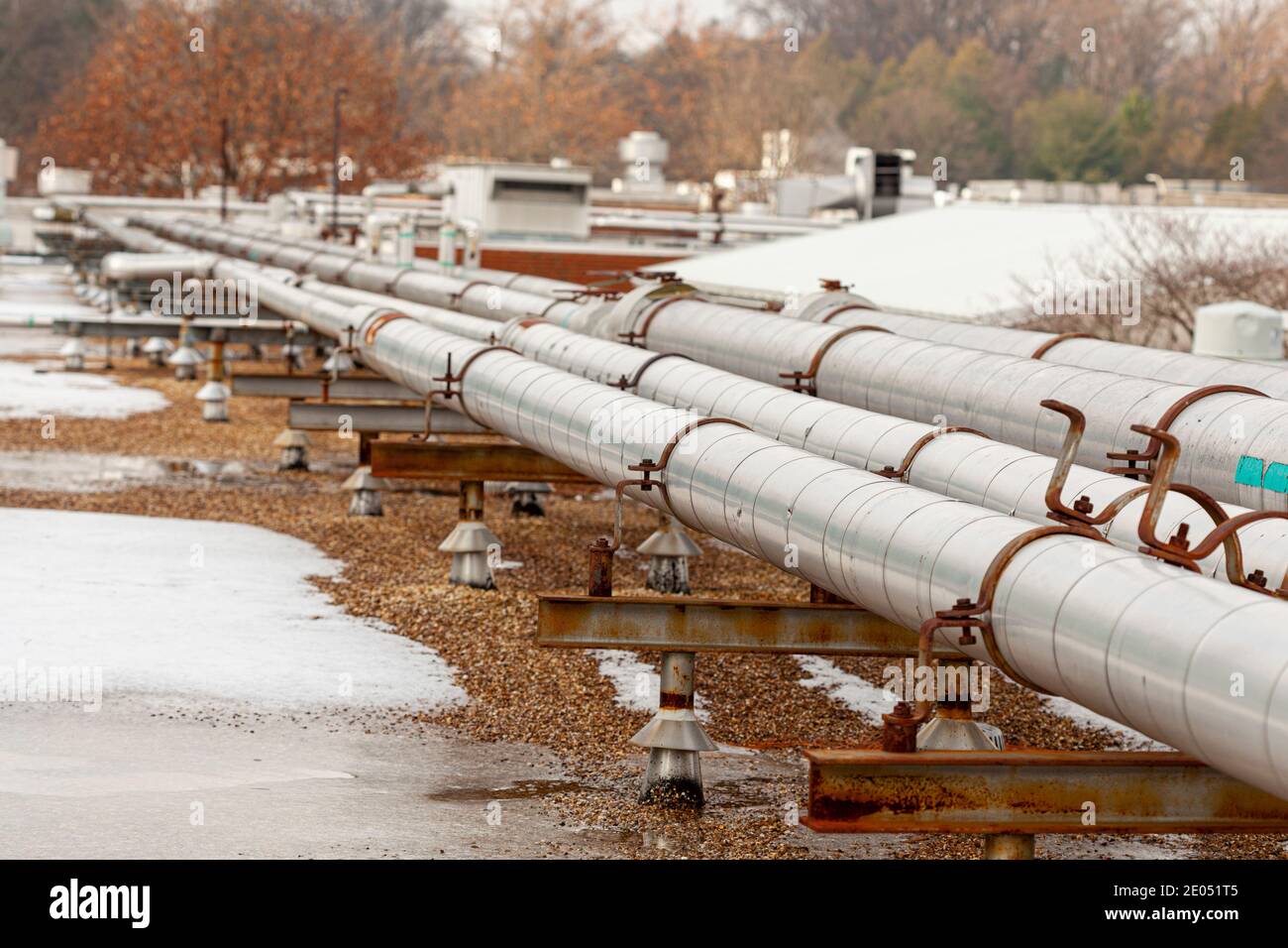 Side view of a pipeline running over snowy terrain near an energy plant ...