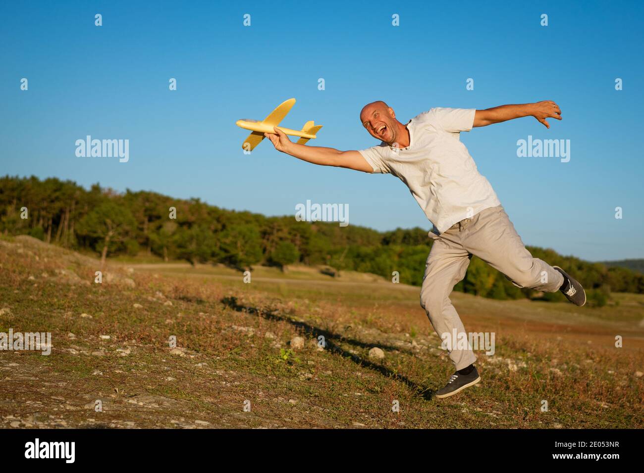 Funny bald man holding an airplane in his hand against the background ...