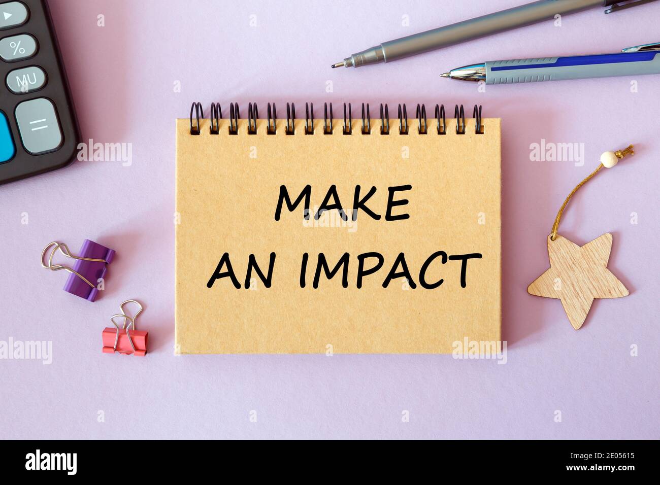 MAKE AN IMPACT is written on a notepad on an office desk with office ...