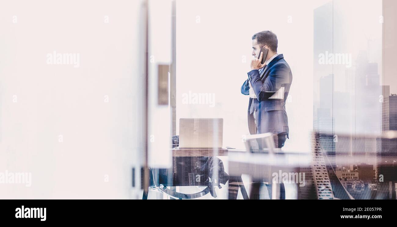 Businessman talking on a mobile phone in corporate office while looking ...