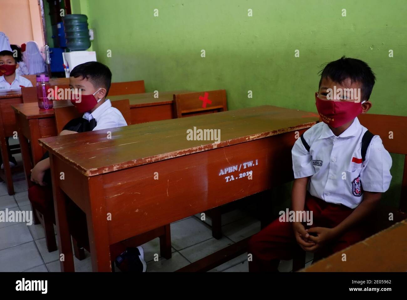 A group of elementary students with face masks inside a classroom of a ...