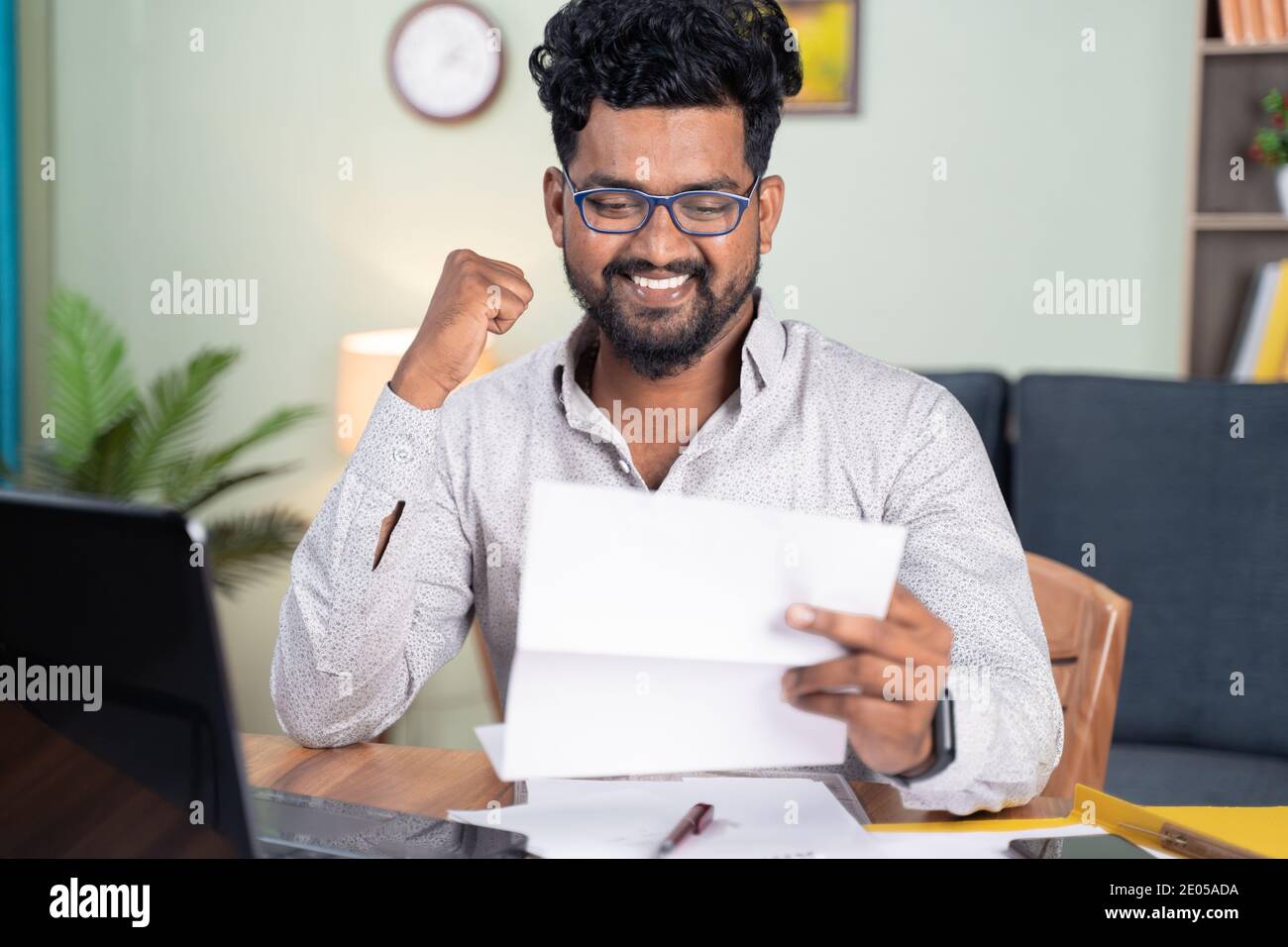 Young man reading paper letter feeling overjoyed by good news clenched ...