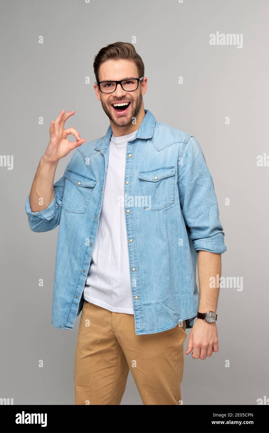 Portrait of young handsome caucasian man in jeans shirt showing ok sign ...