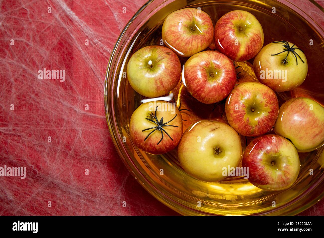 A Halloween apple bobbing game on a spooky cobweb layered red halloween ...