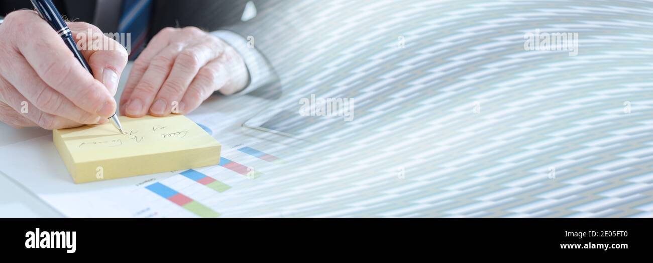 Businessman taking notes on a post-it; panoramic banner Stock Photo - Alamy