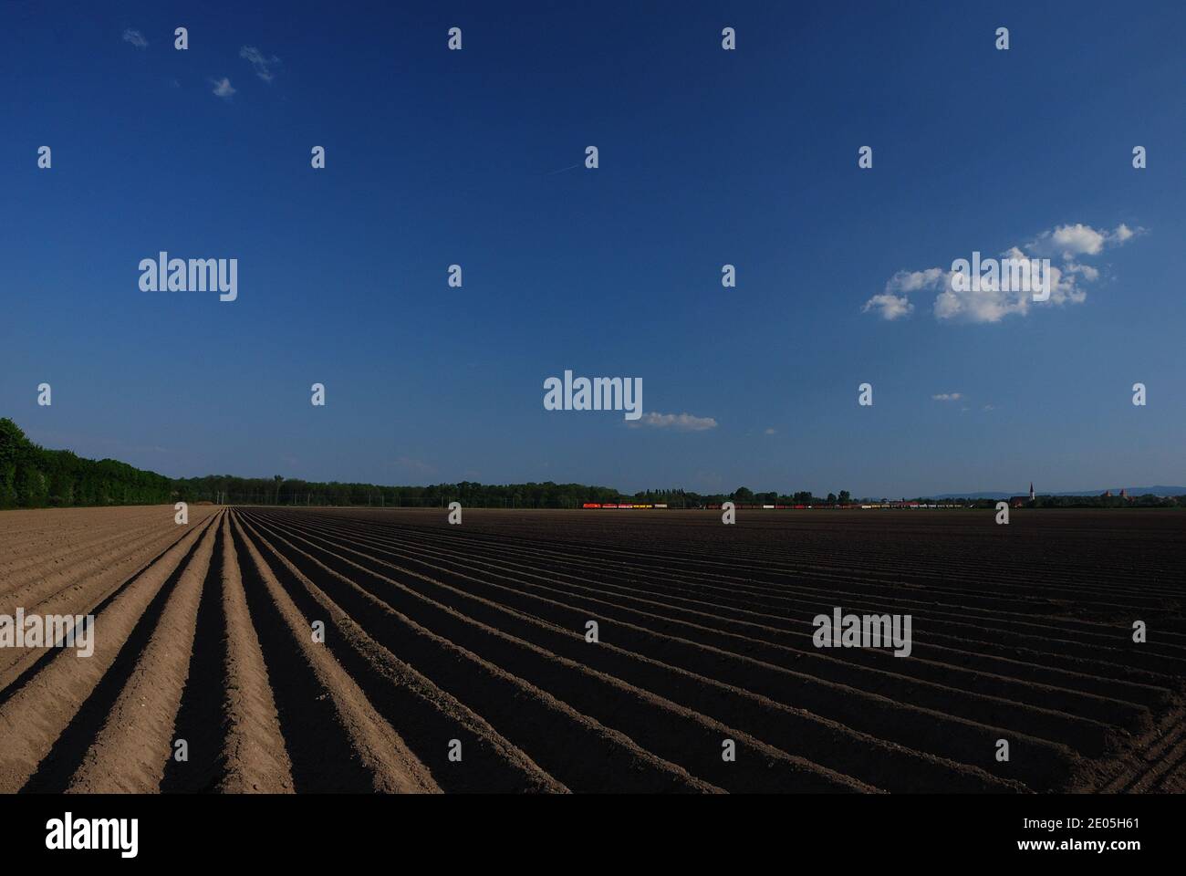 well plowed farmland with straight lines and train with blue sky Stock ...
