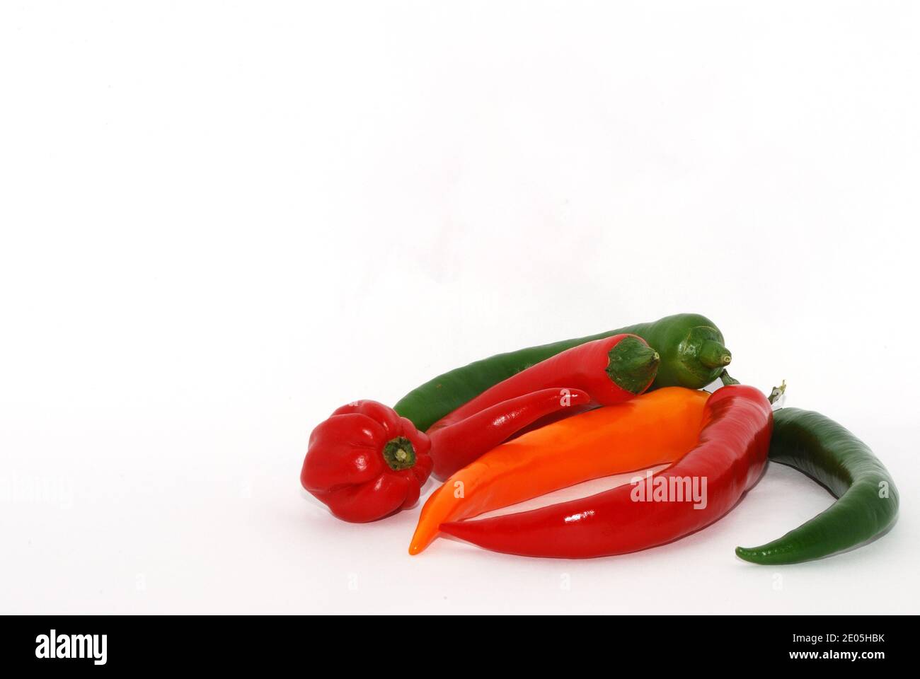 different colored hot chili on white background right Stock Photo - Alamy
