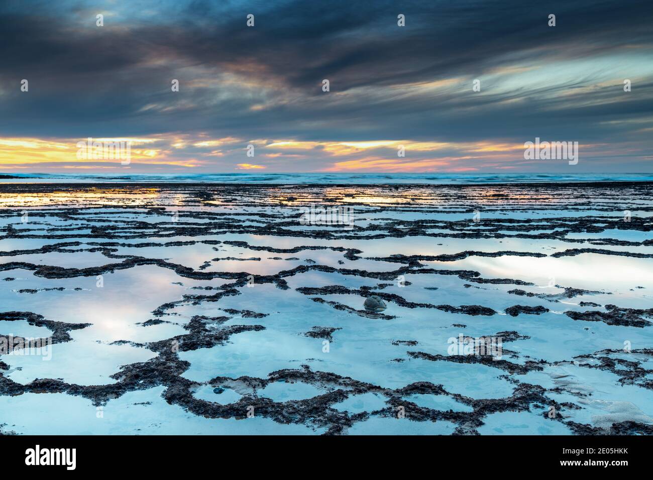 A beautiful sunset over the ocean with rocky beach and tidal pools in ...