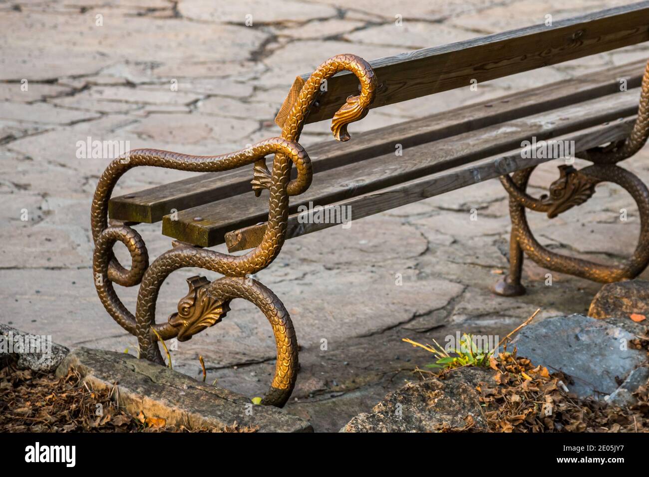 Bench in the park at sunset with metal railing in the form of a snake ...