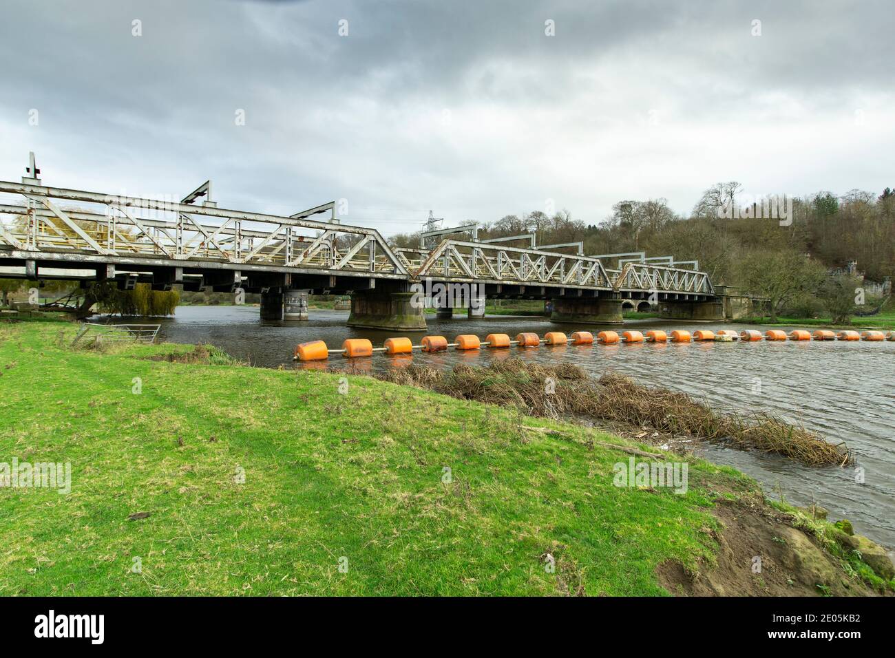 Orange safety boom stretched across a river in front of a railway ...